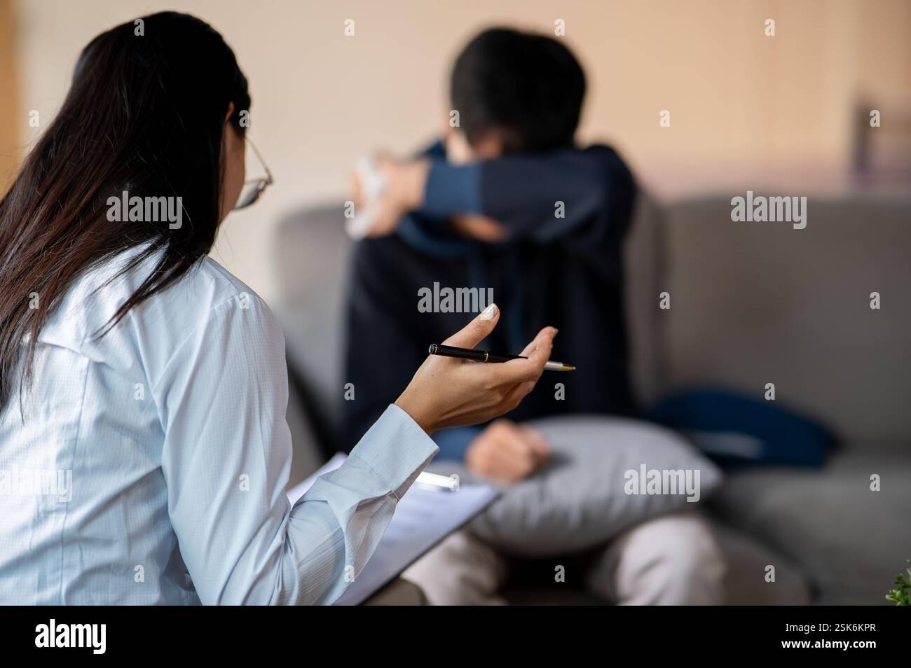 A back view of a female psychologist talking with her patient in the ...