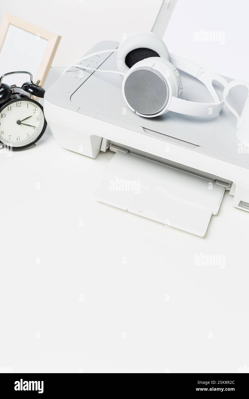 Compact workspace featuring a printer, headphones, clock, and picture ...