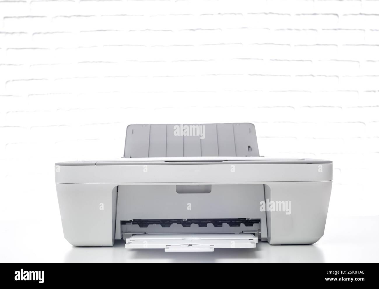 Modern printer positioned against a bright white brick wall in a ...