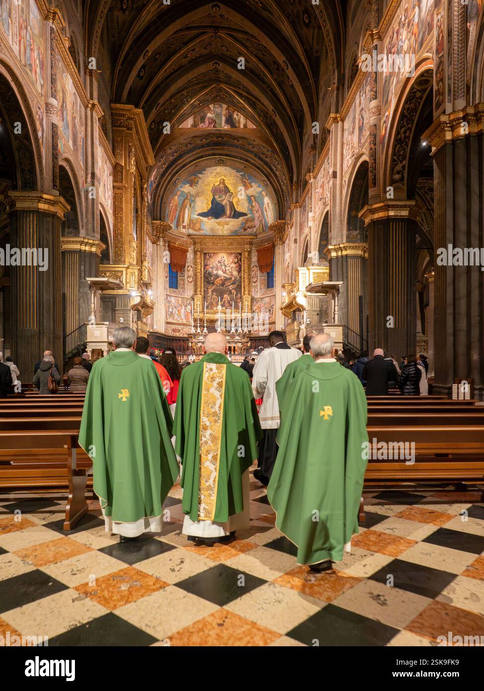 Cremona, Italy - February 9th 2025 Priests wearing green chasubles walking in the nave during a ...