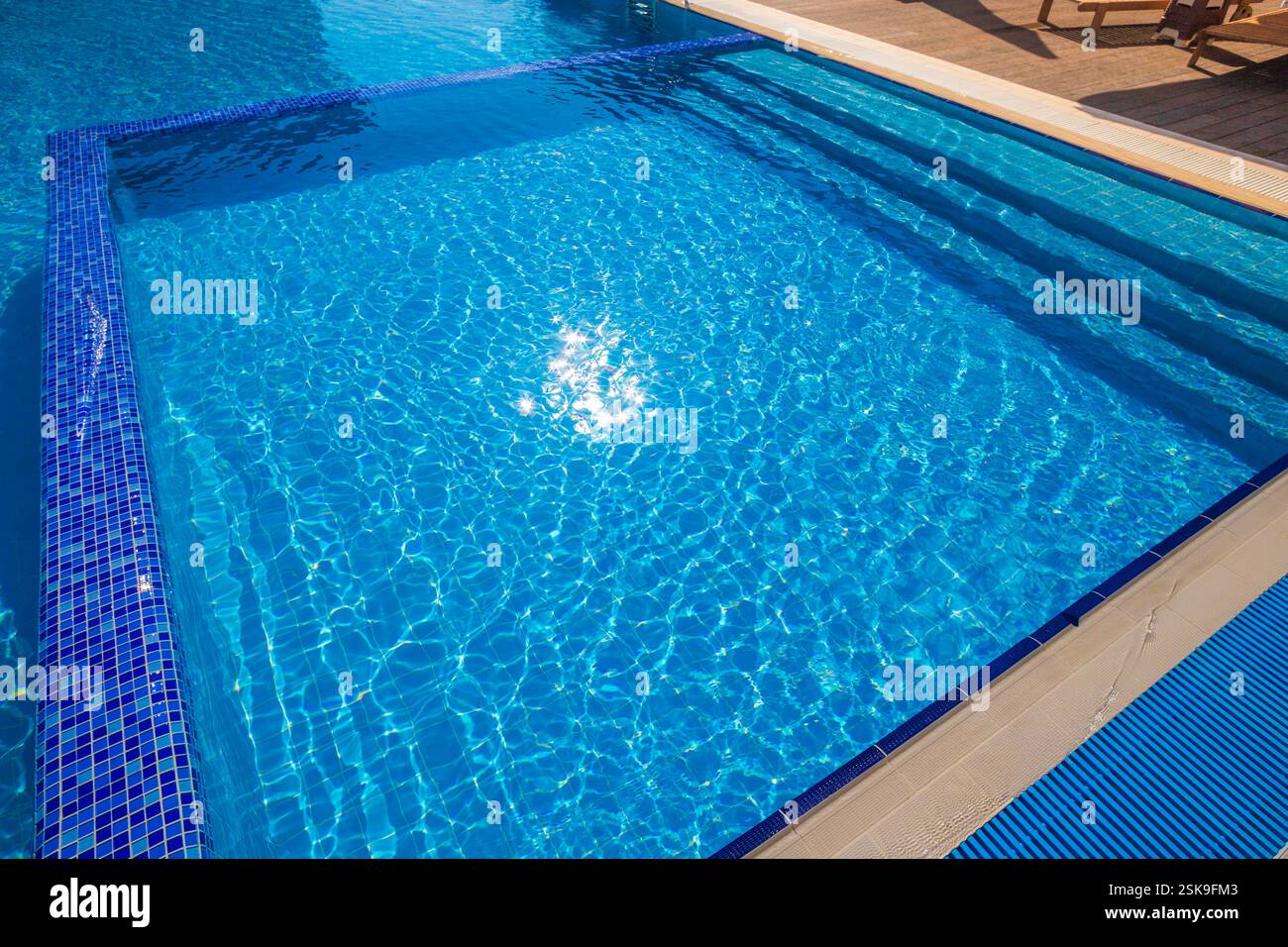 Bright sunlight reflecting on clear blue water in a refreshing swimming ...