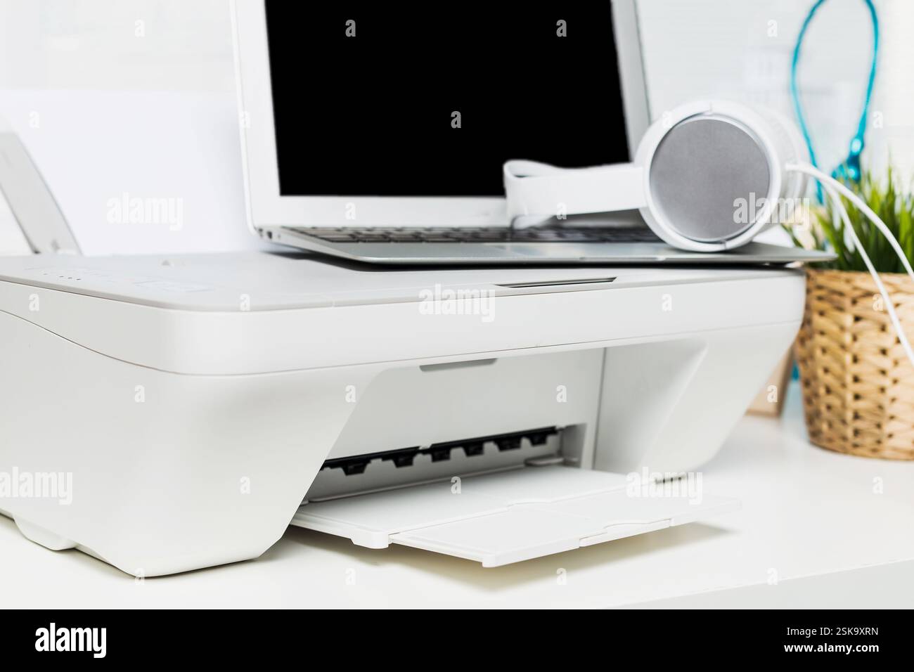 Modern home office setup with printer, laptop, and headphones on a desk ...