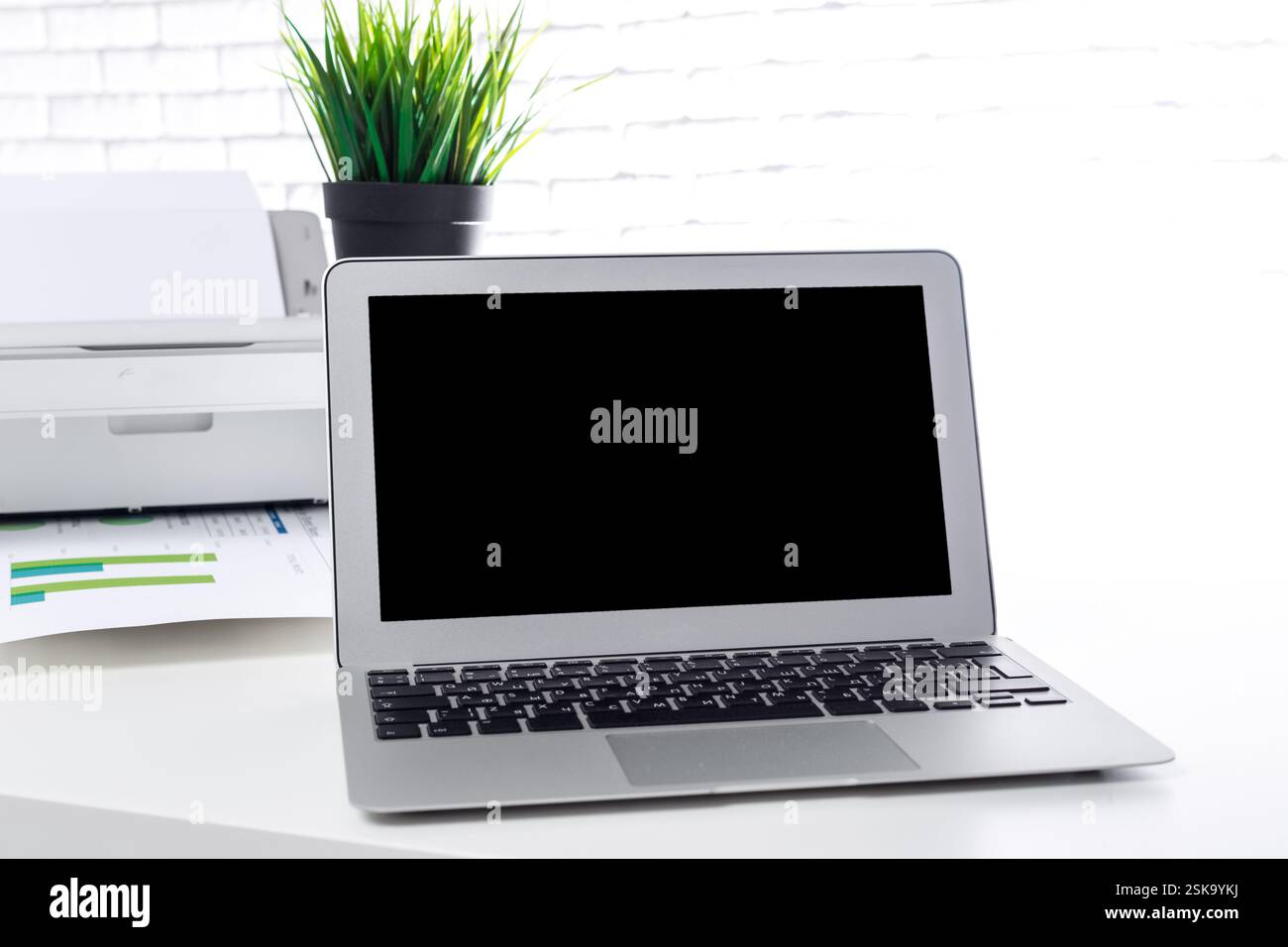 Modern workspace setup featuring a laptop and printer in a bright ...