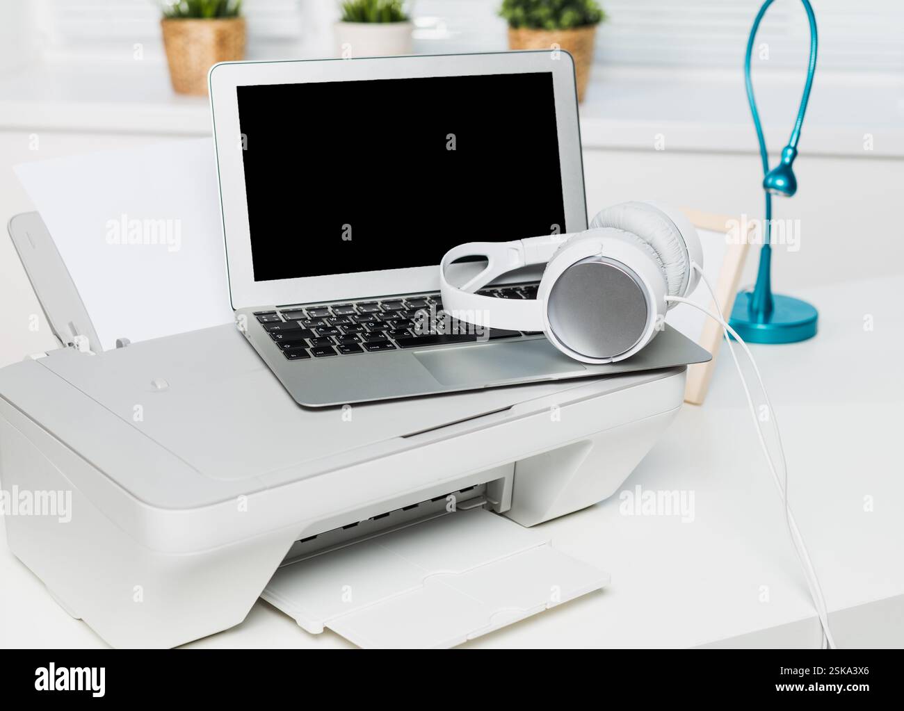 Modern workspace setup with laptop, printer, and headphones in a bright ...
