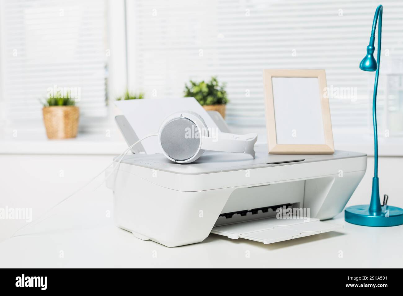 Home office setup featuring a printer, headphones, lamp, and empty ...