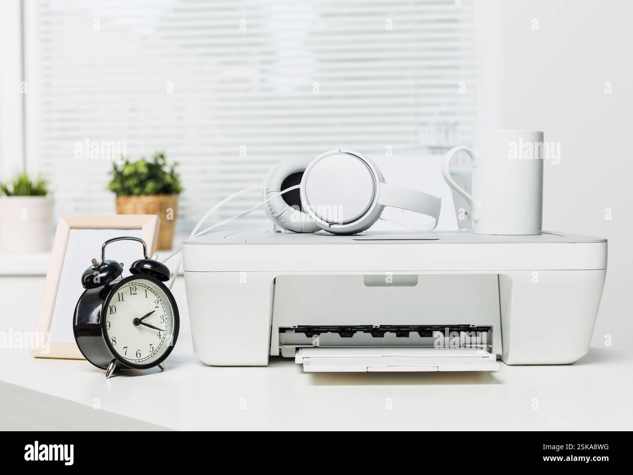 Modern workspace with printer, clock, headphones, and coffee cup ...