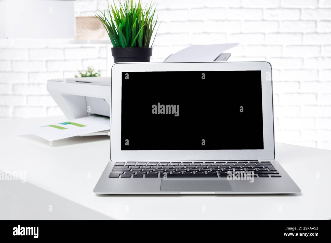 Modern workspace featuring a laptop, printer, and indoor plants on a ...