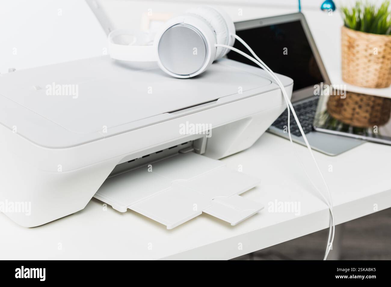 Modern workspace with printer and laptop featuring headphones on a ...