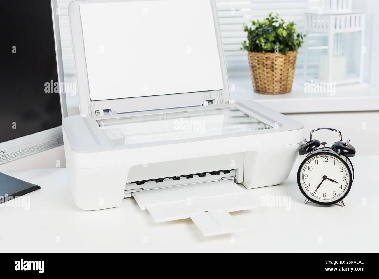 White printer on desk with alarm clock and plant indoors during daytime ...