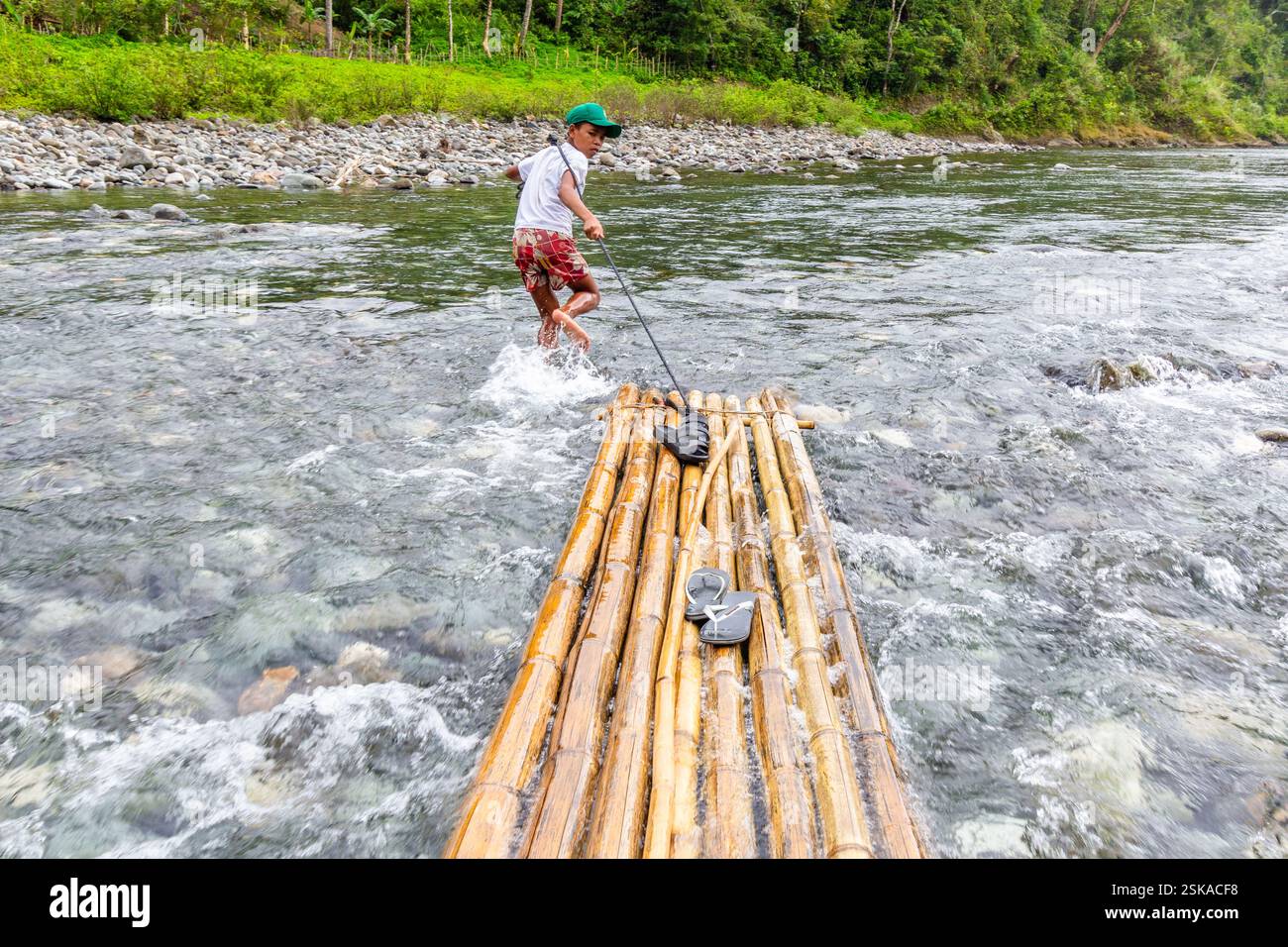 A Filipino boy leads his bamboo raft through the shallow parts of ...