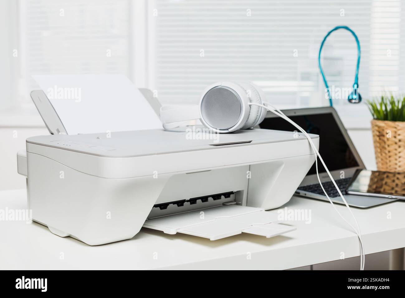 Home office setup with printer, laptop, and headphones in a bright ...