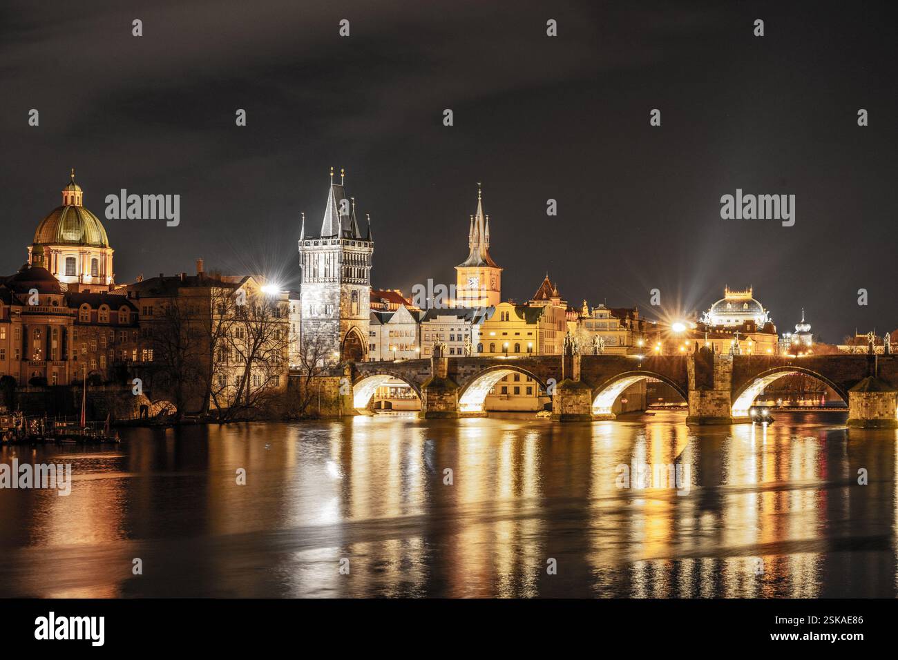 Nighttime reveals the stunning beauty of Charles Bridge, with its arches reflecting in the calm ...
