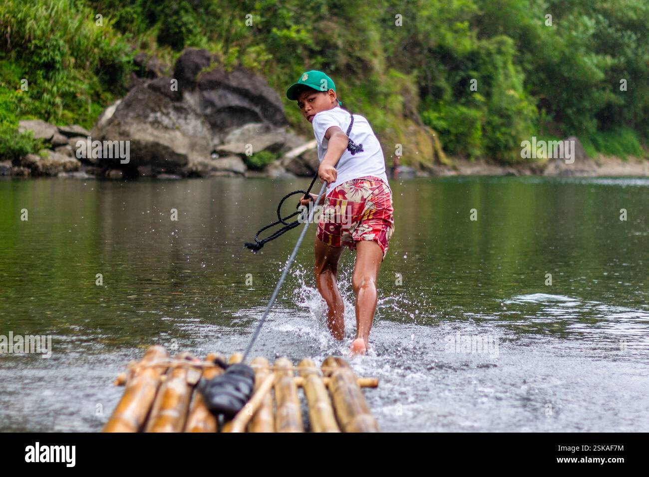 A Filipino boy leads his bamboo raft through the shallow parts of ...