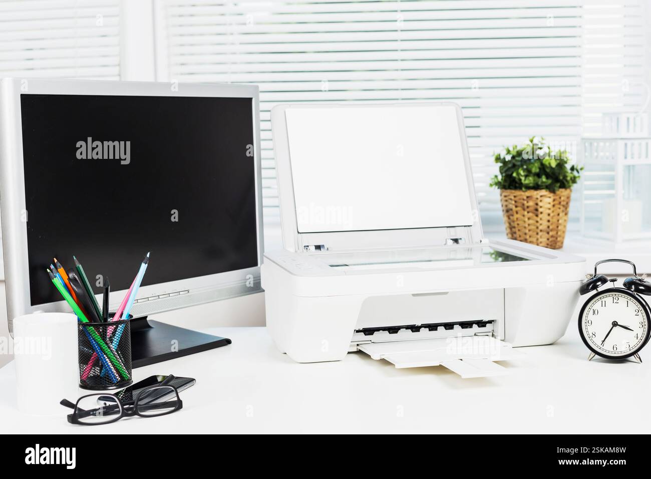 Compact workspace featuring a printer, monitor, and office supplies in ...