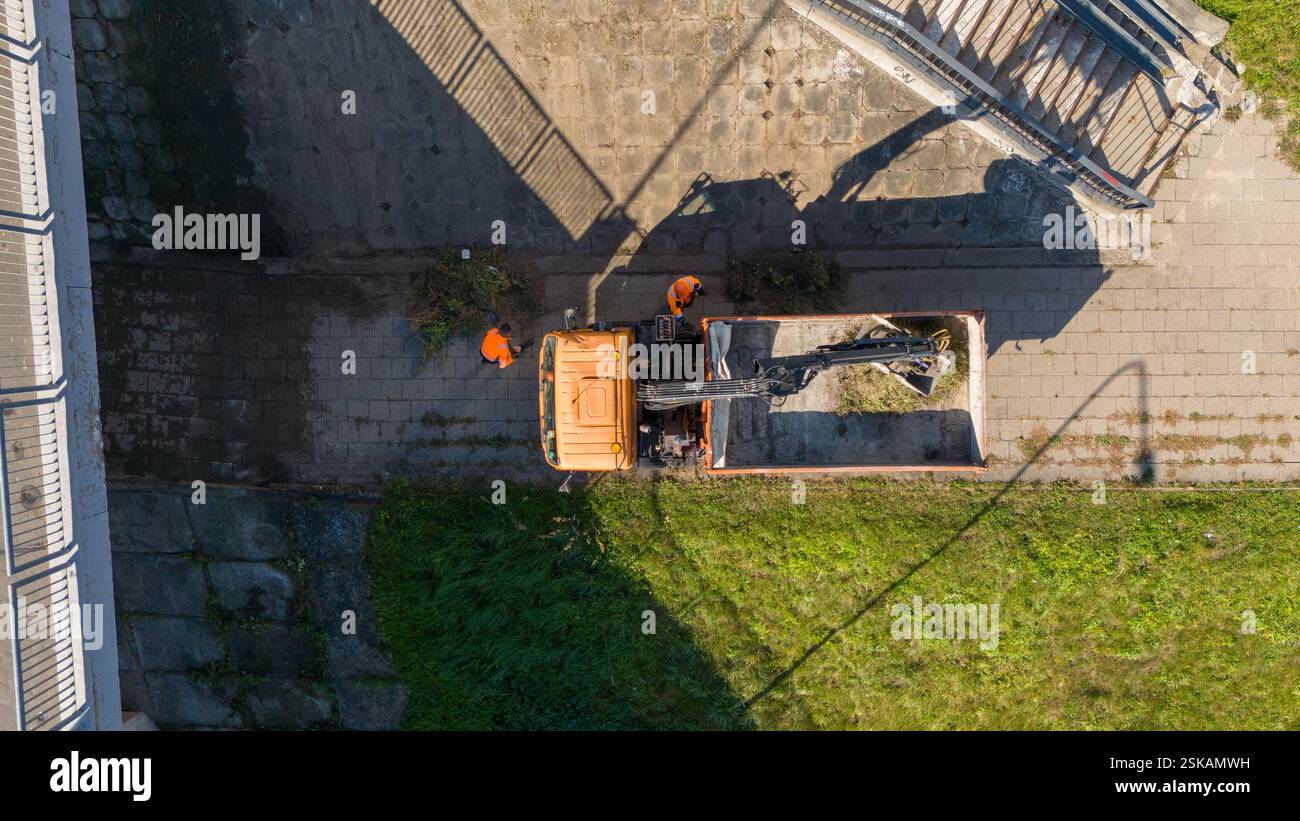 An aerial view of construction workers operating a digger on a sidewalk ...