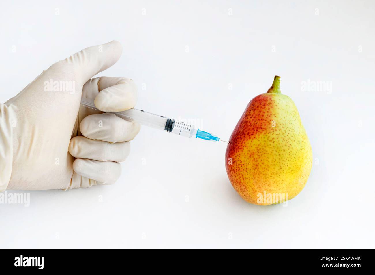 A pear and a hand with a syringe on isolated white background ...