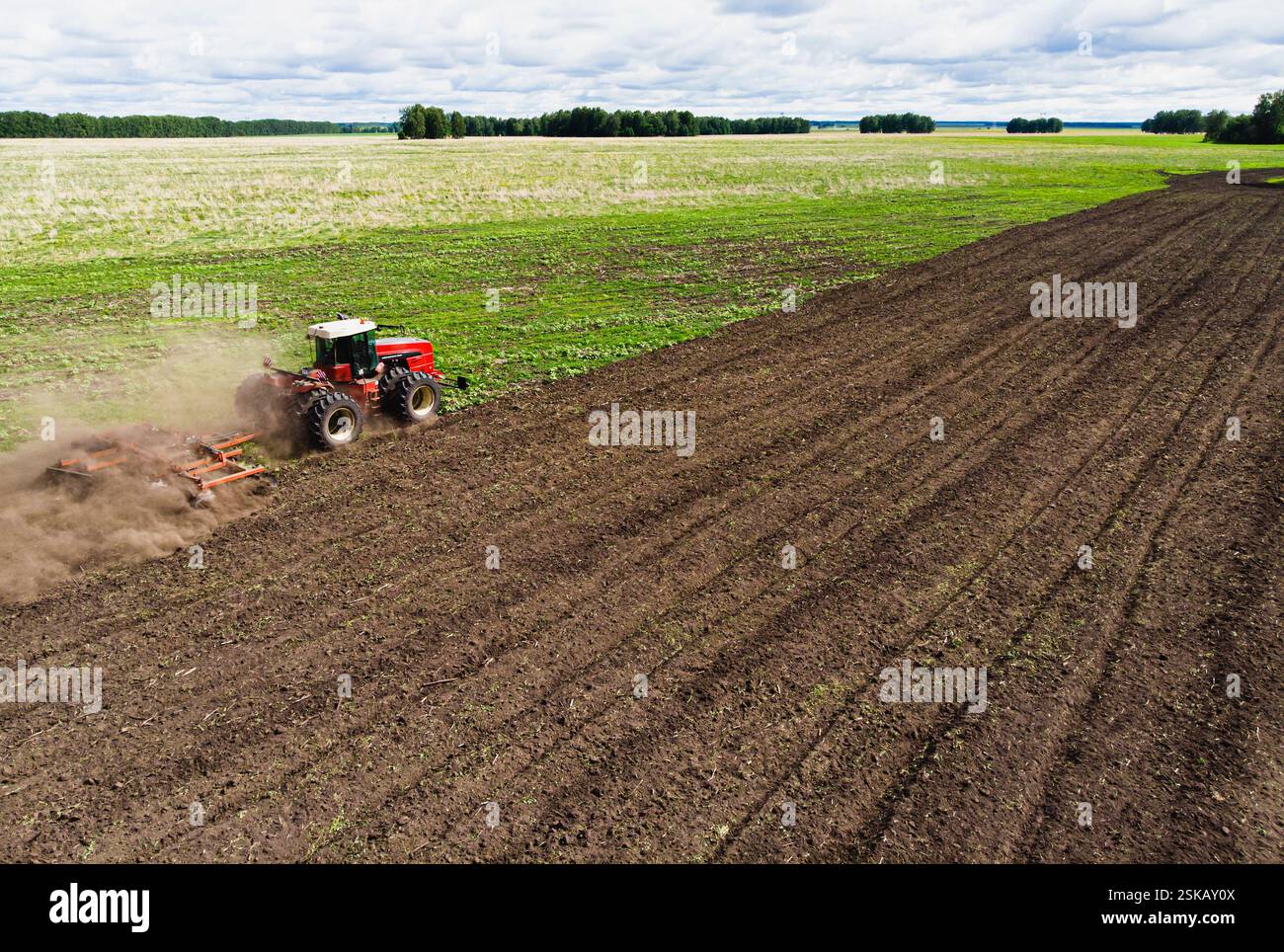 A large agricultural machine cultivates the land. The view from the top ...