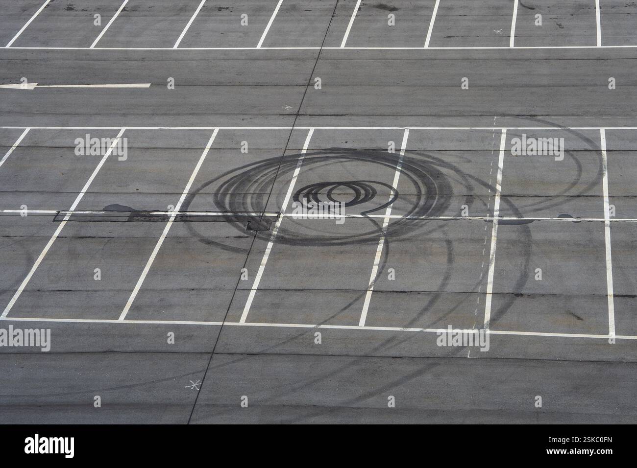 Aerial view of empty parking lot. Gray asphalt shows marks drifting car ...