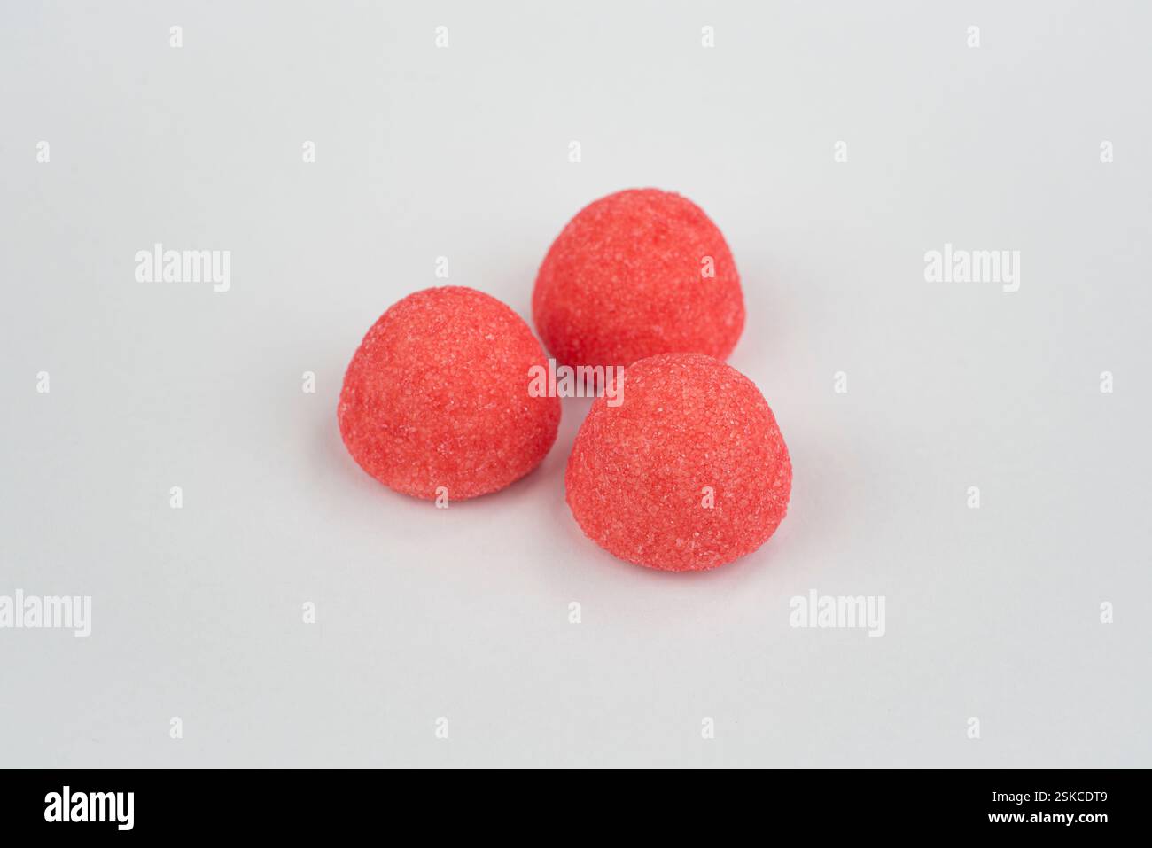 Red strawberry candies on a light grey background Stock Photo - Alamy