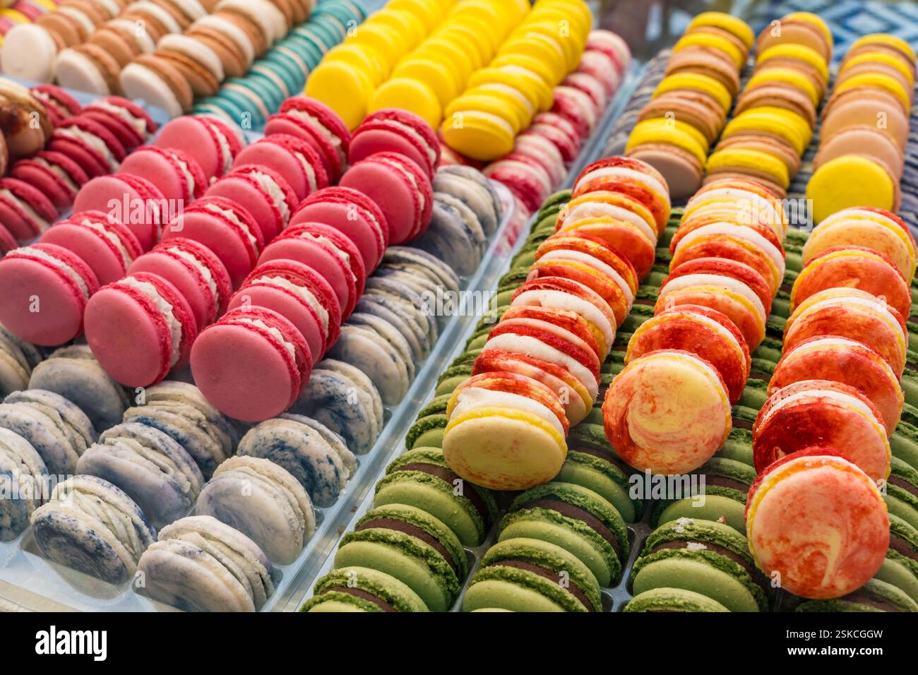 Colorful assorted macarons neatly arranged in a pastry shop display ...