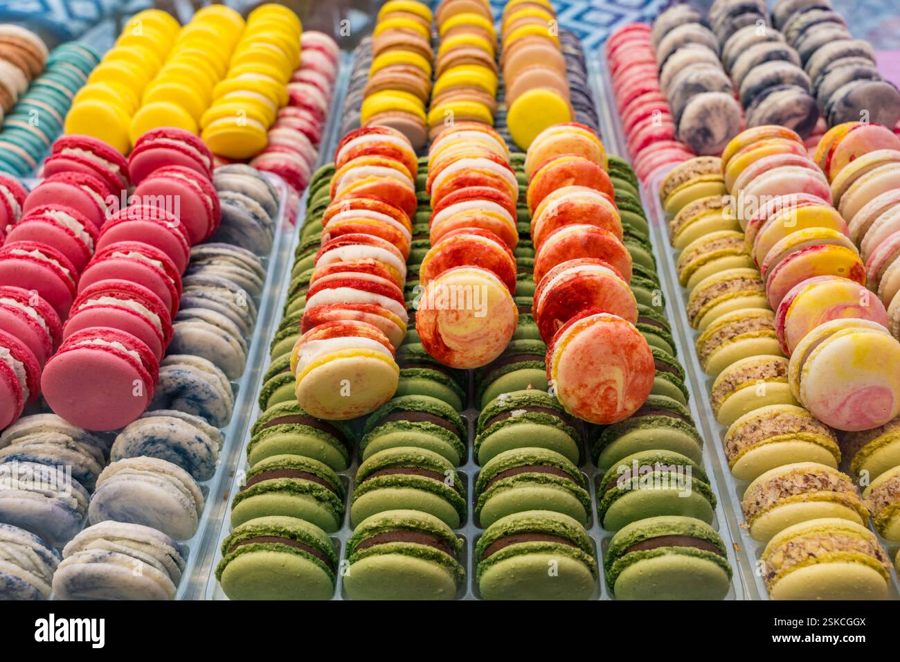 Colorful assorted macarons neatly arranged in a pastry shop display ...
