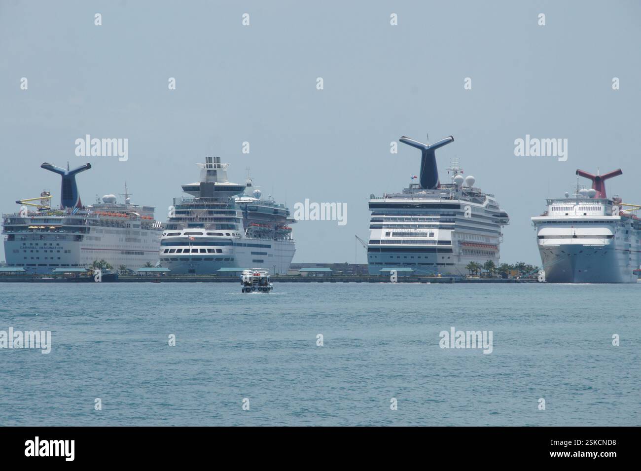 The photo shows four cruise ships docked in a harbor. Their white hulls ...