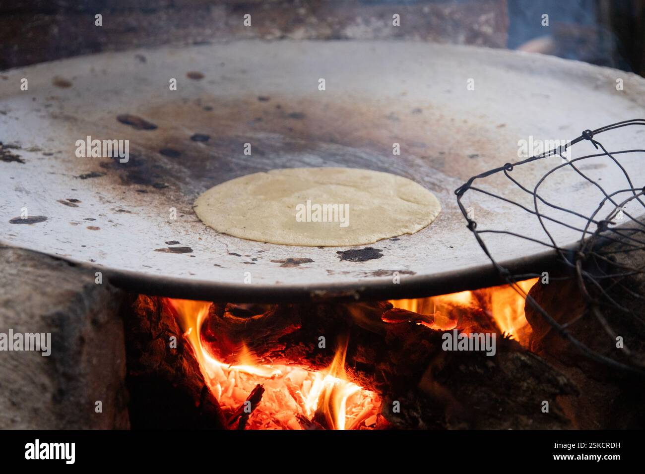 Cooking handmade corn tortillas on a traditional comal in an open fire ...