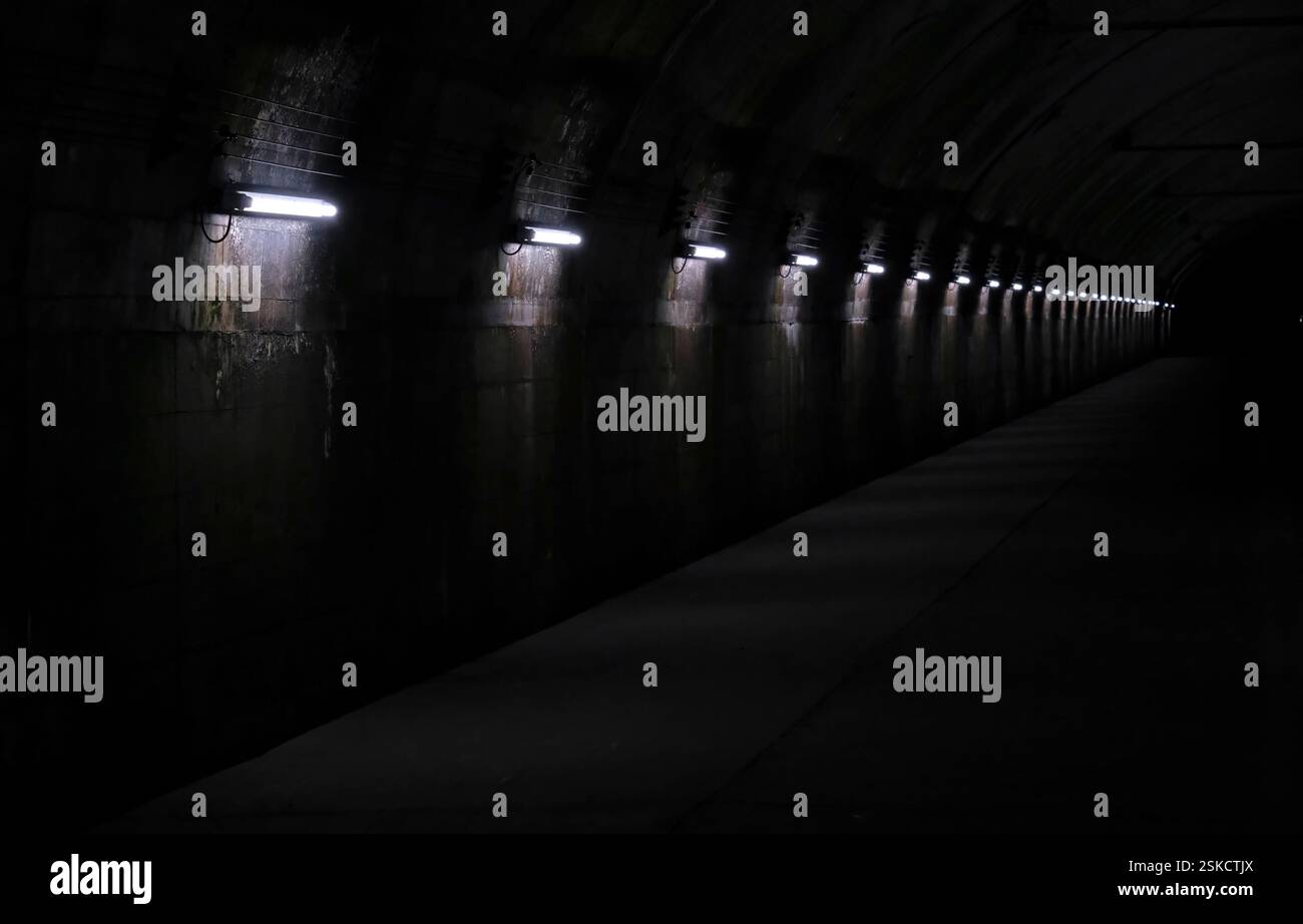 Dark underground corridor barely illuminated by fluorescent tubes Stock ...