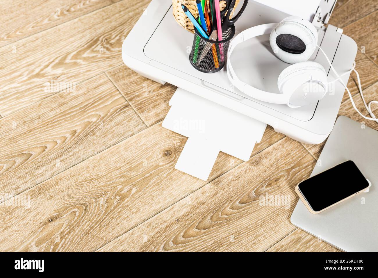 Workspace setup with printer, headphones, laptop, and smartphone on ...