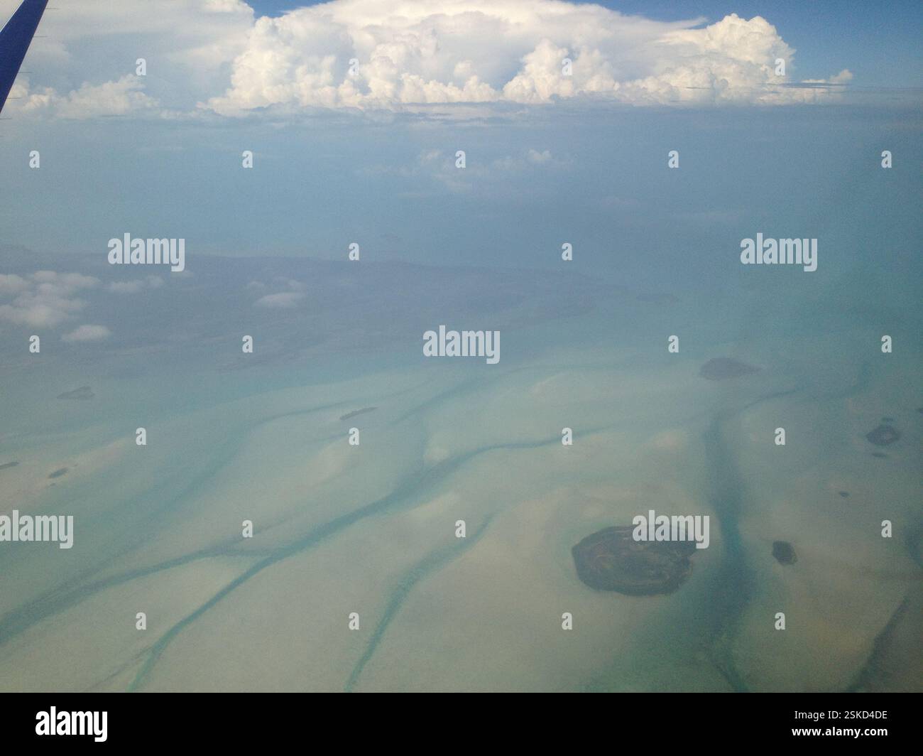 Aerial view of turquoise ocean with white clouds and dark blue shadows ...