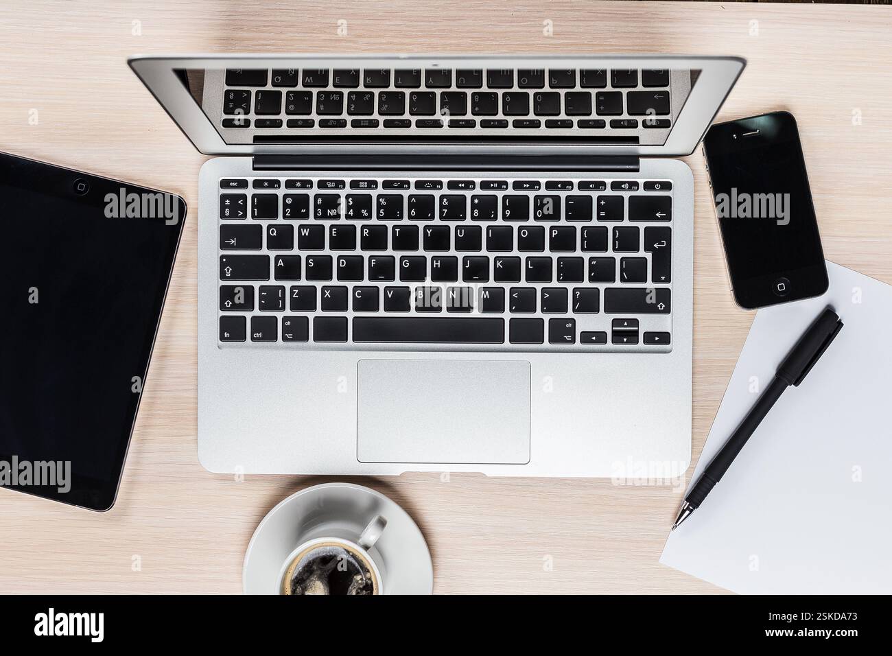 Modern workspace features a laptop, tablet, smartphone, coffee cup, and ...