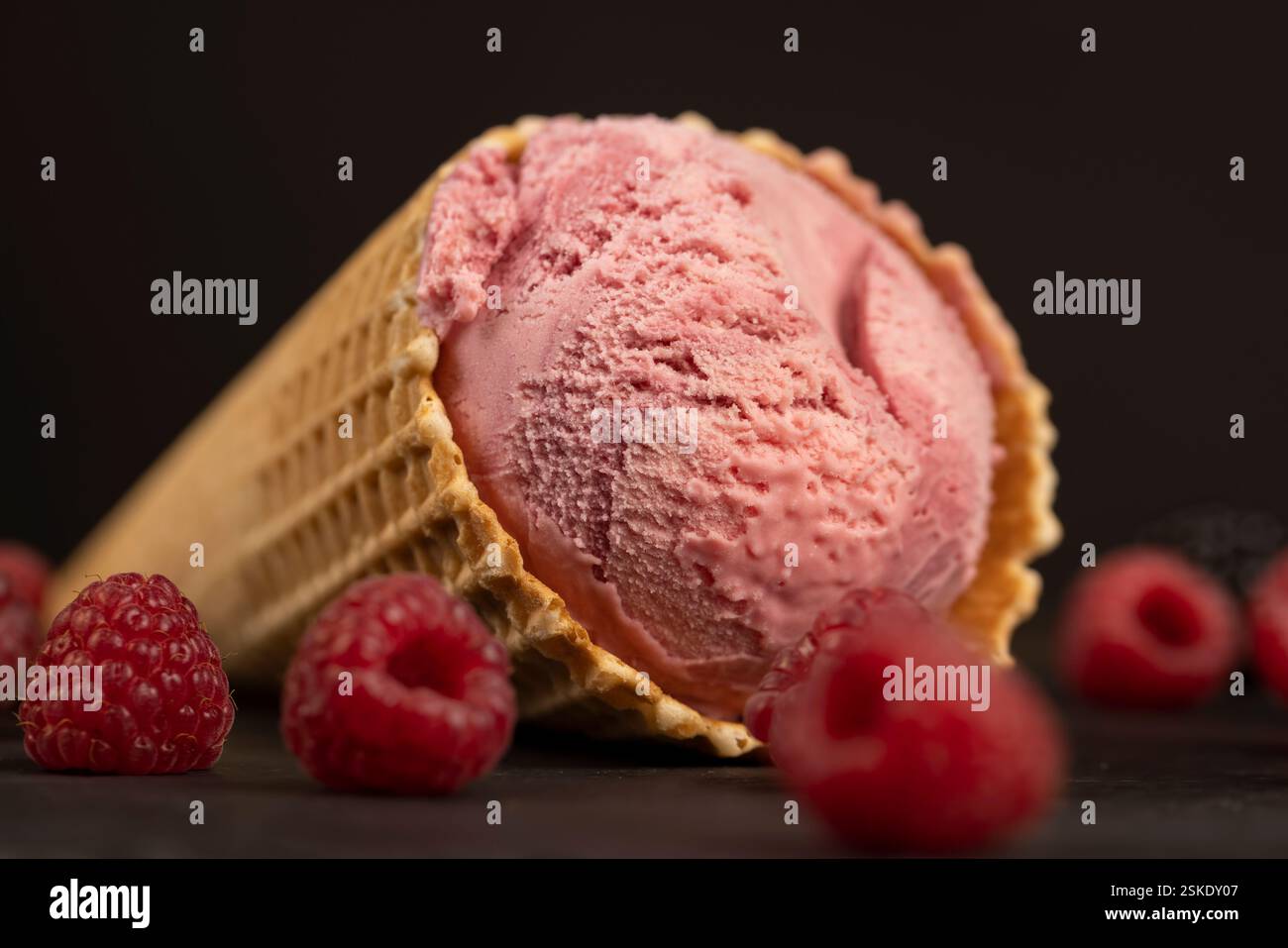 raspberry ice cream in a waffle cone on a black background, delicious ...