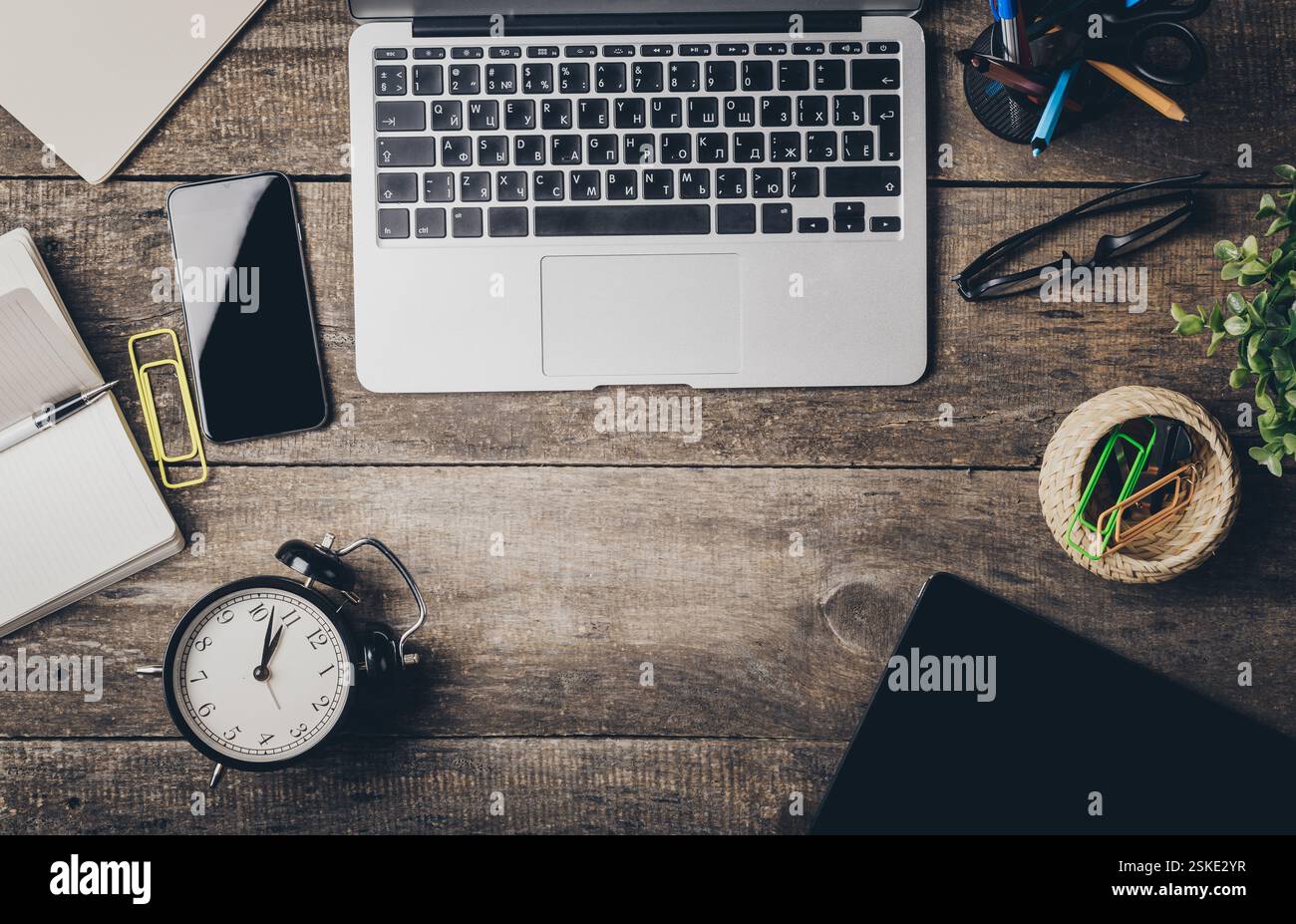 Workstation setup featuring a laptop, smartphone, clock, and stationery ...