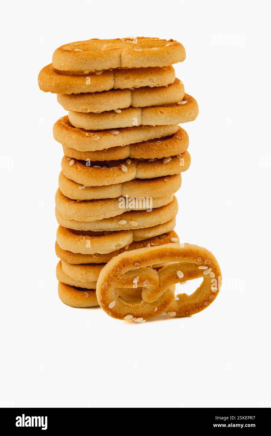 A tower of golden-brown pretzels is standing on a white surface, with ...
