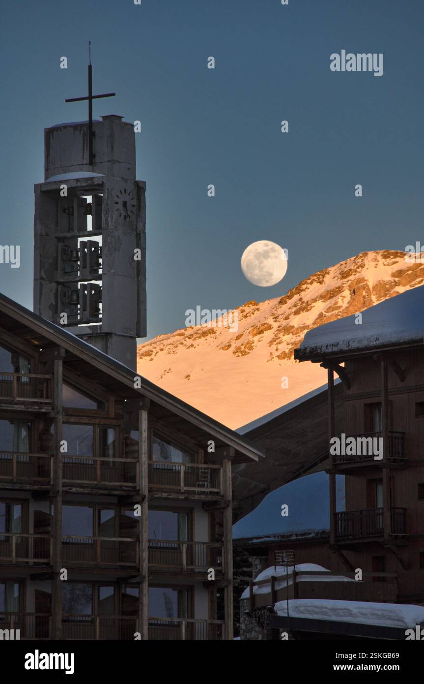 vertical view of the full moon rising above a snowy mountain peak, with ...