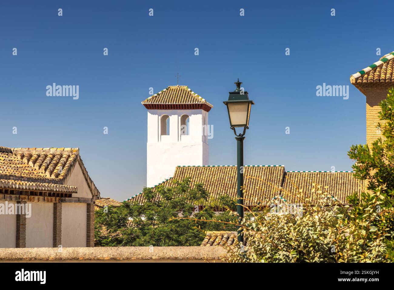 Granada town in Spain. White tower and terracotta rooftops under a ...