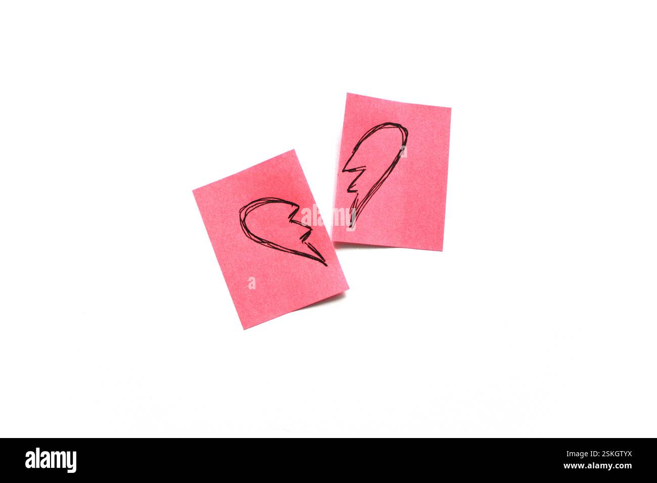 Two pieces of pink sticky note torn apart with two parts of a broken ...