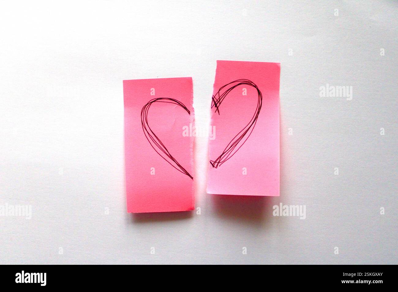 Two pieces of pink sticky note torn apart with two parts of a broken ...