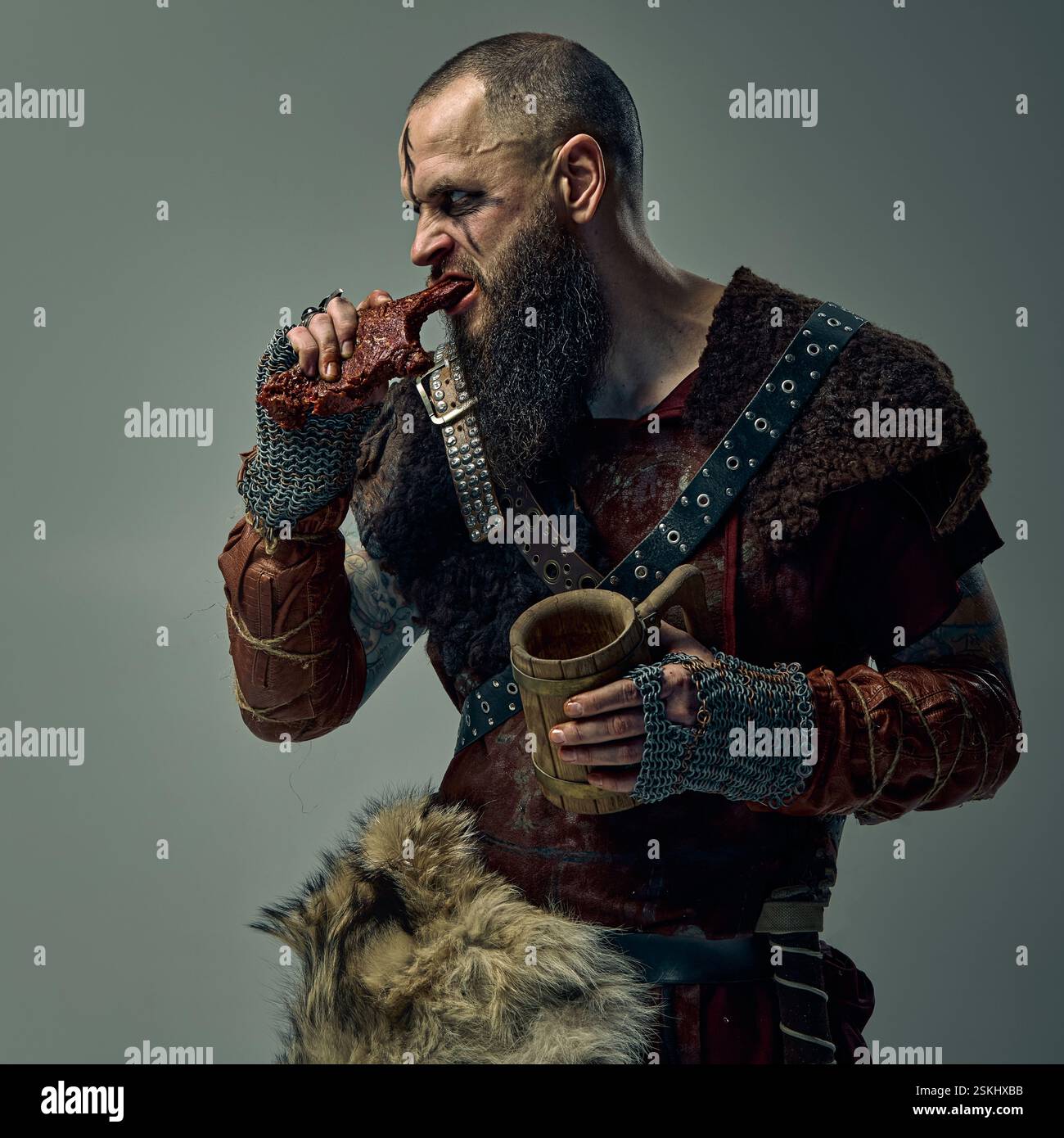 Close-up of Viking warrior with intense gaze biting raw meat, holding ...
