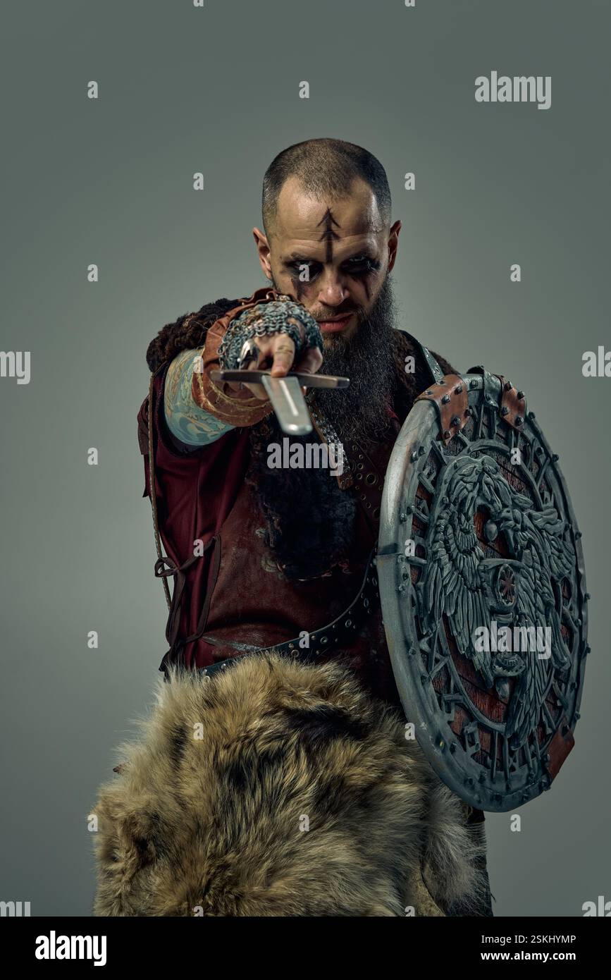 Portrait of Viking warrior gripping sword and shield, pointing blade ...