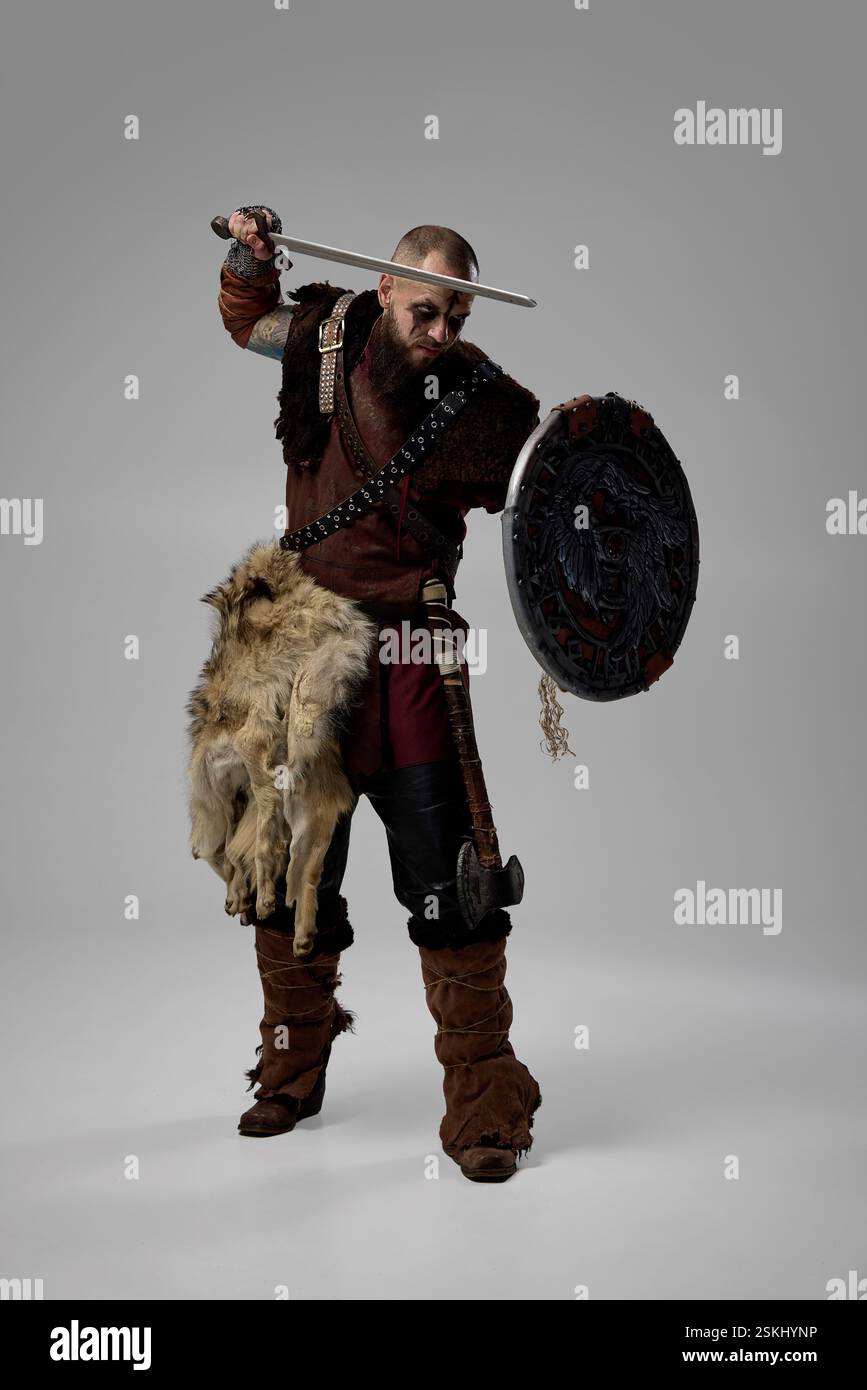 Man dressed as Viking warrior in fur cloak and leather armor holding ...