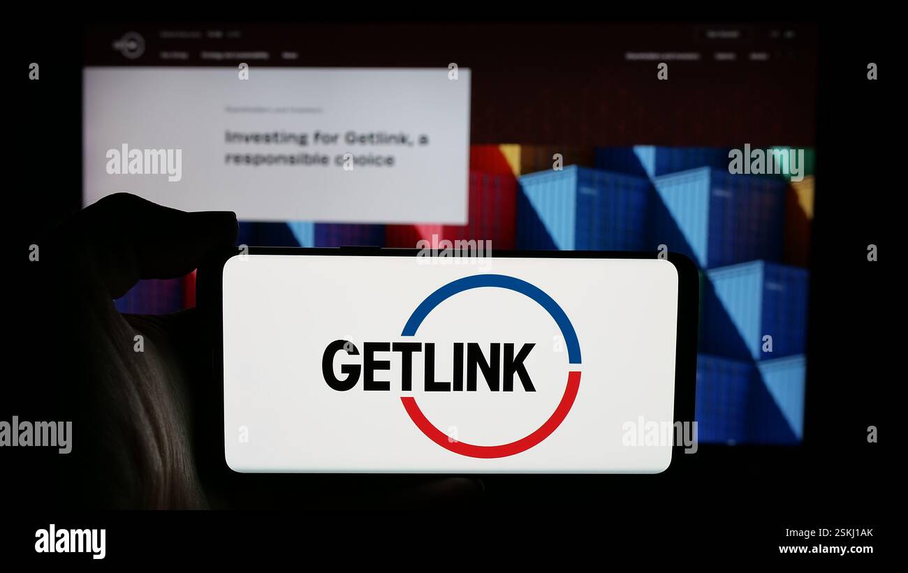 In this photo illustration, a person is holding a cellphone with the logo of Channel Tunnel ...