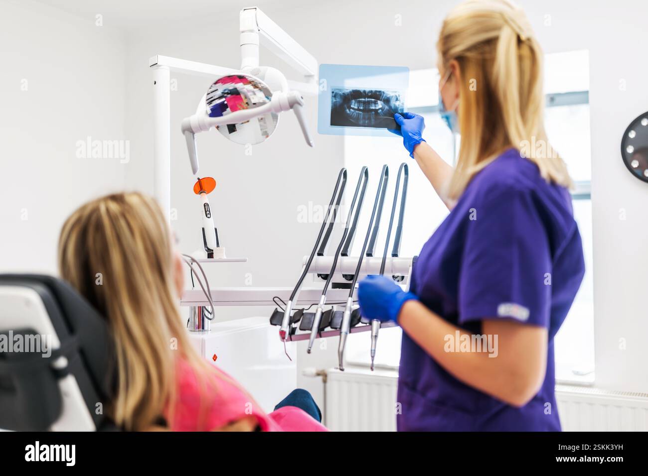 Dentist is examining x-ray image of jaw and teeth with her patient ...