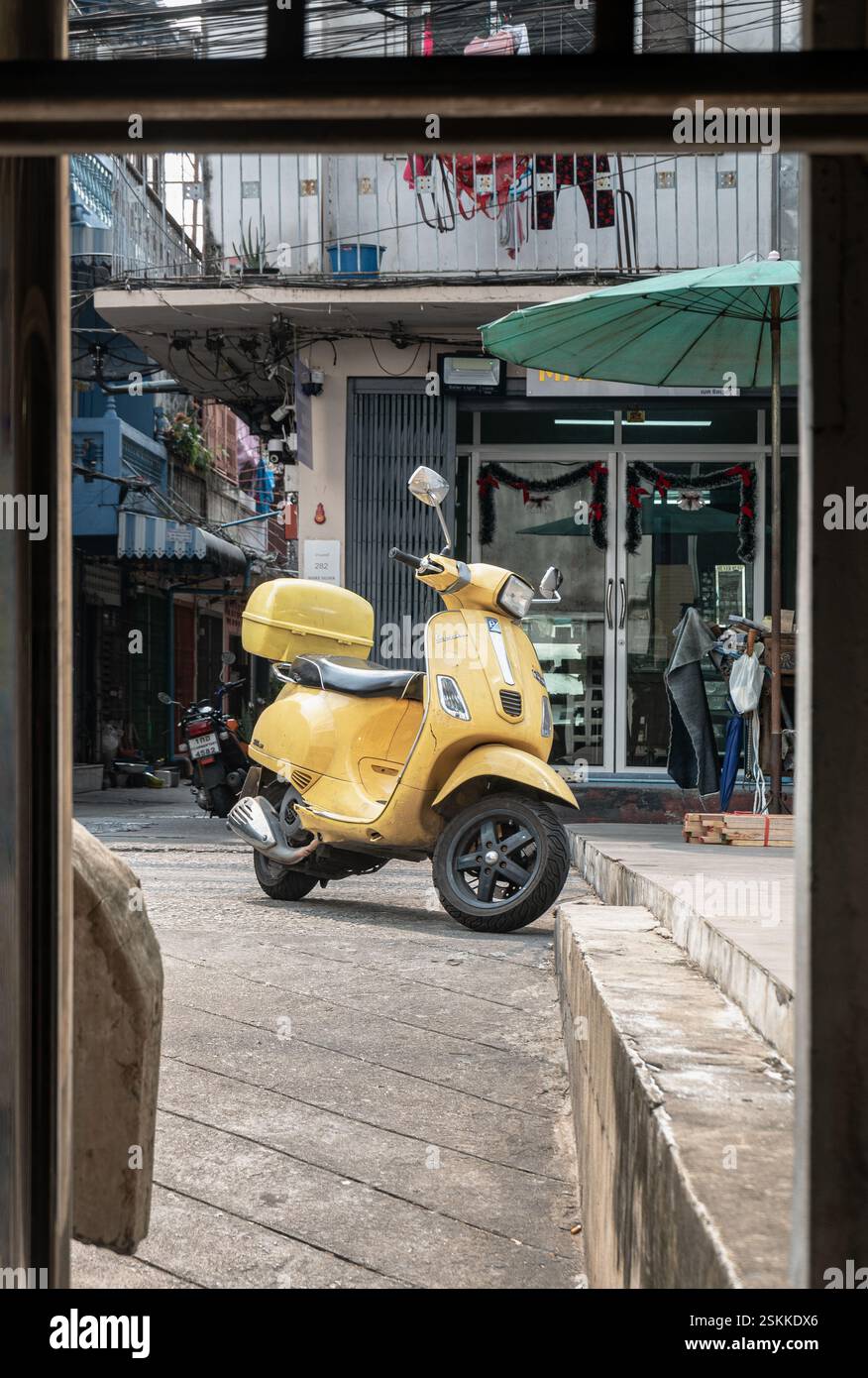 Bangkok, Thailand - Feb 09, 2025 - A Yellow vespa scooter parked on the street at a neighborhood ...