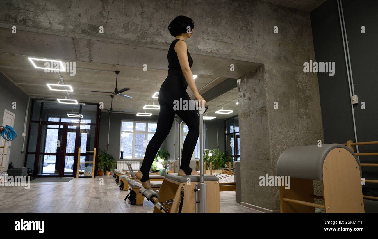 Professional Pilates instructor demonstrates step-up exercise on ...