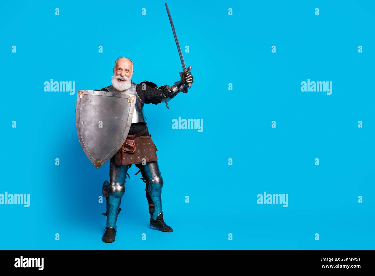 Elderly man dressed as a regal knight holding sword and shield against ...