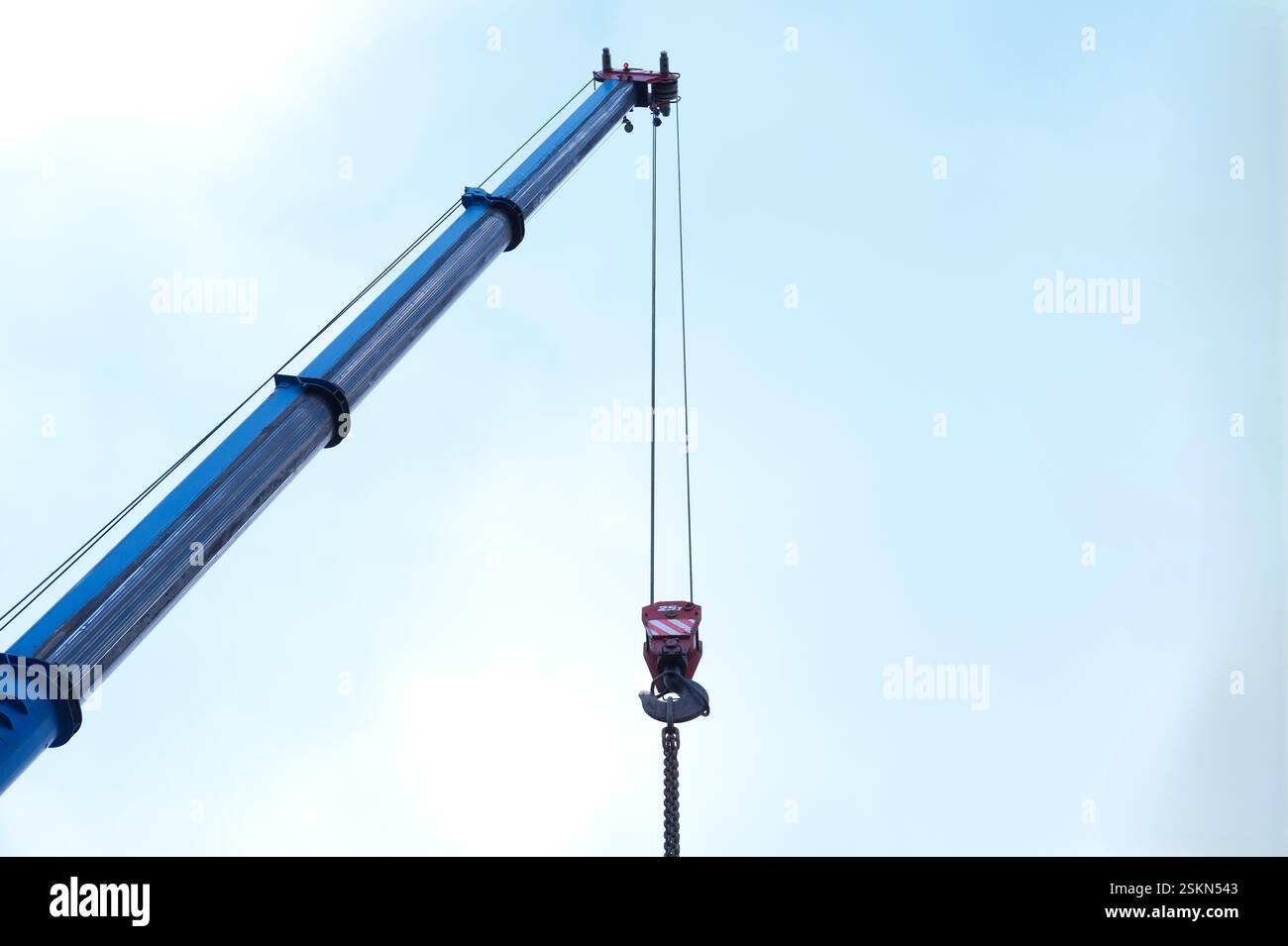 Blue crane arm, boom with hanging hook against clear sky. Construction ...