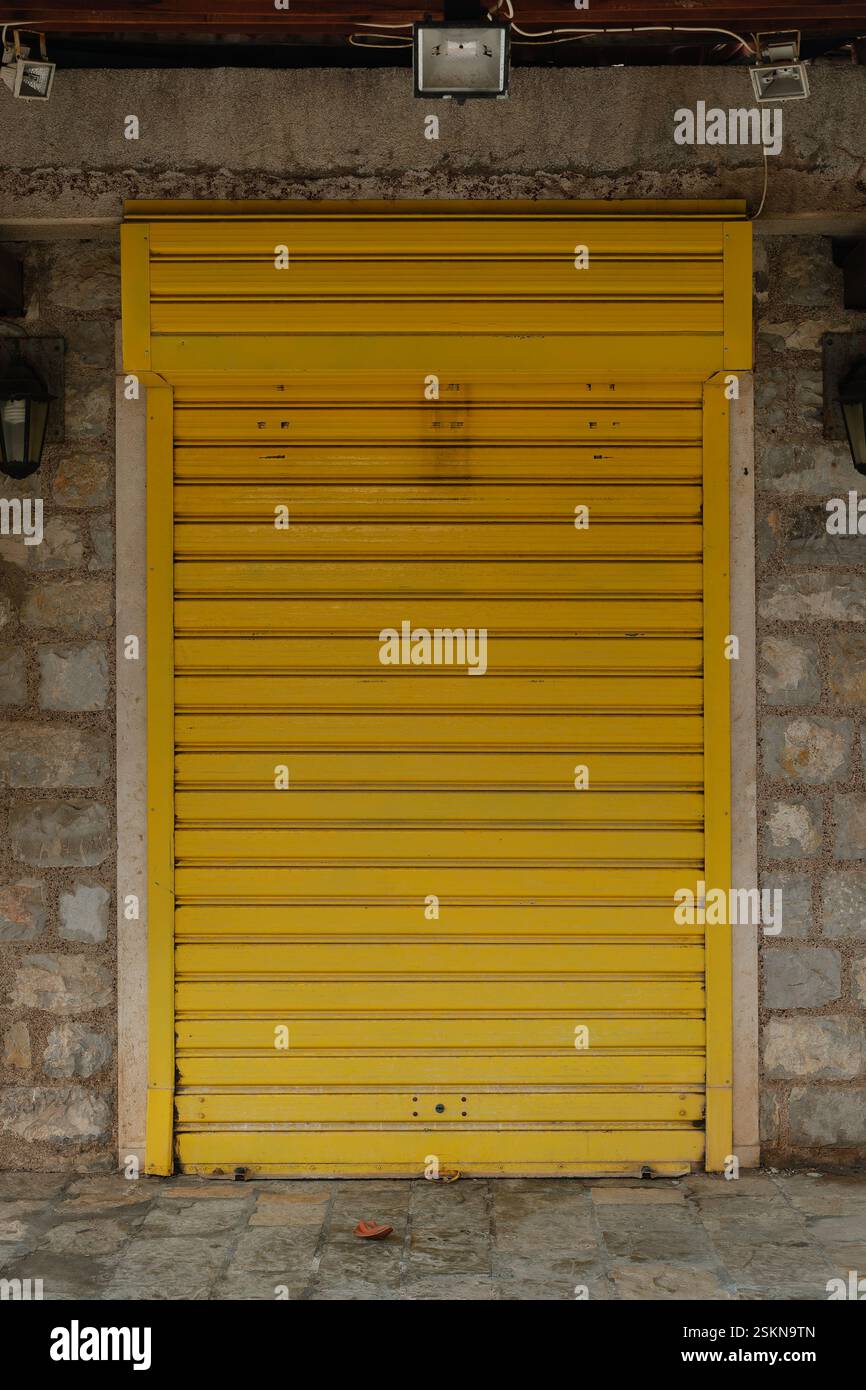 Slightly rusty yellow metal rolling door on a stone wall Stock Photo ...