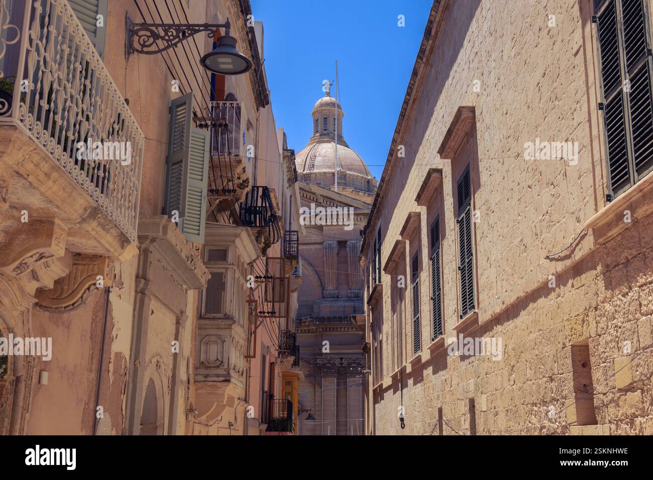 Traditional Maltese limestone buildings with balconies in alley street ...