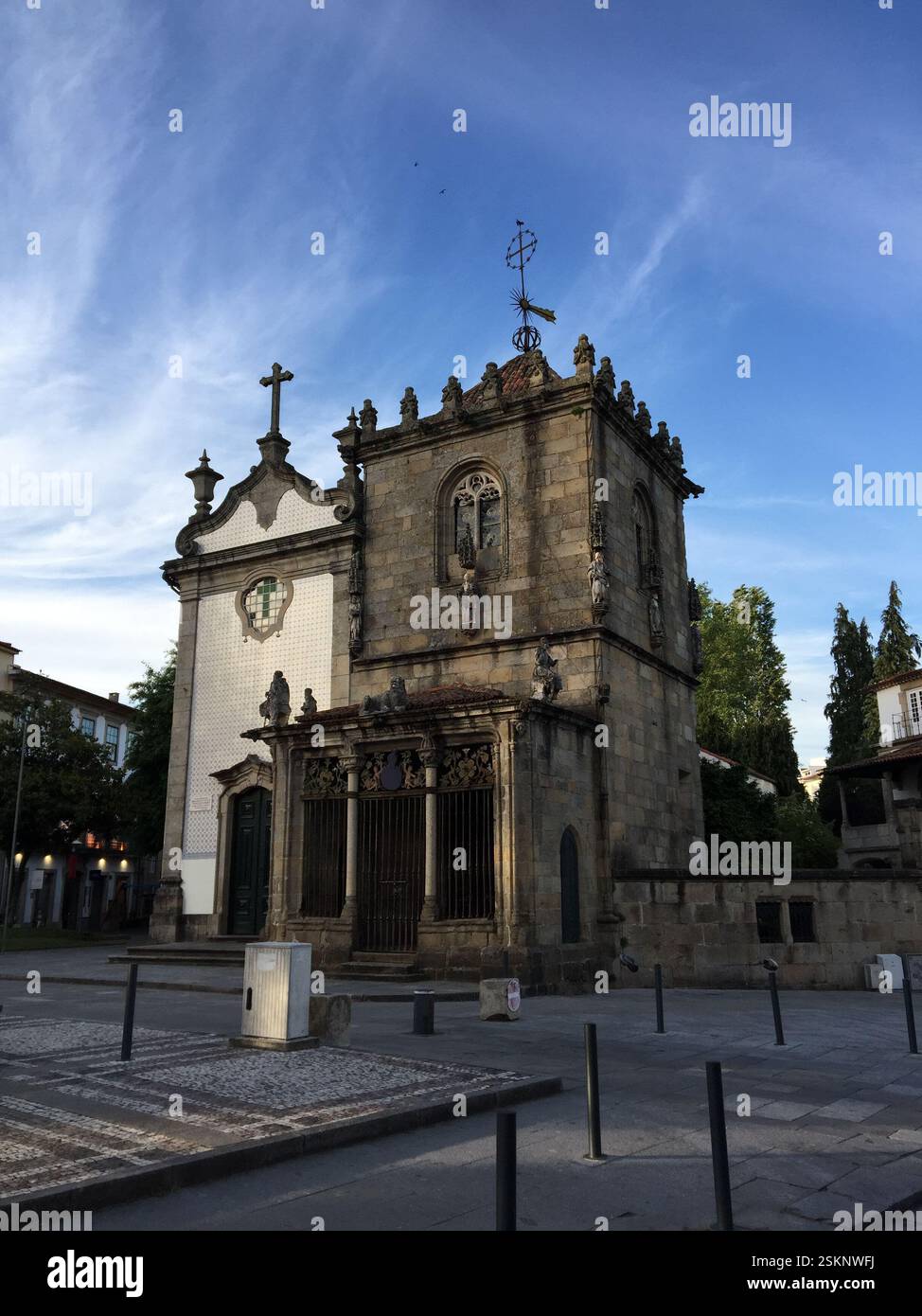 Stone chapel with ornate details, crowned by a cross, stands amidst the ...